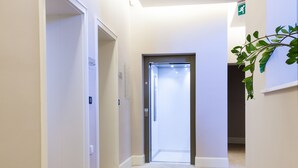 Um corredor com piso coberto por carpete, paredes brancas e portas que dão para os quartos.