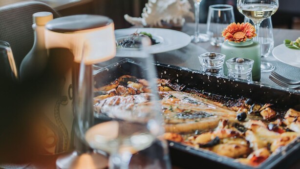 Mesa de jantar posta com pratos, copos e uma travessa de comida.