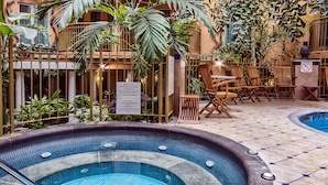 Área de spa com hidromassagem, cadeiras de madeira e piso ladrilhado.