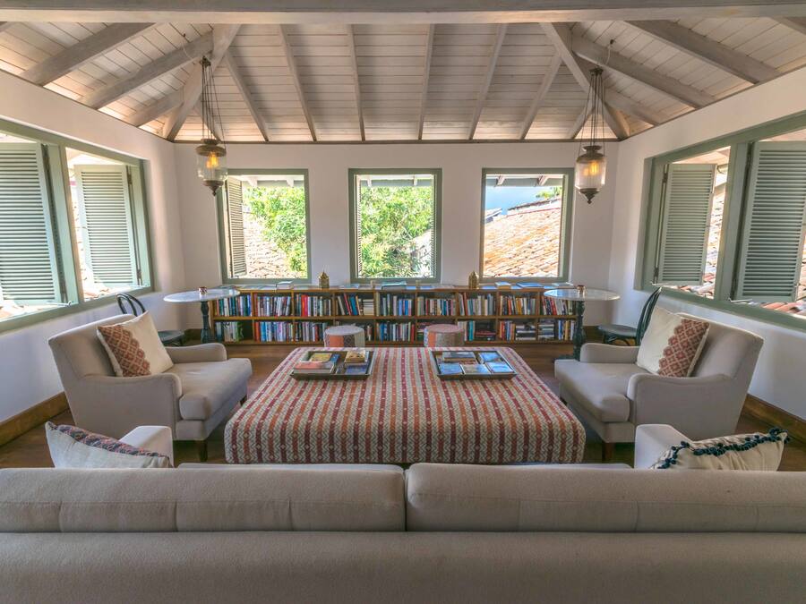 Um espaço de leitura aconchegante, com um amplo sofá, uma mesinha de centro e uma estante cheia de livros.