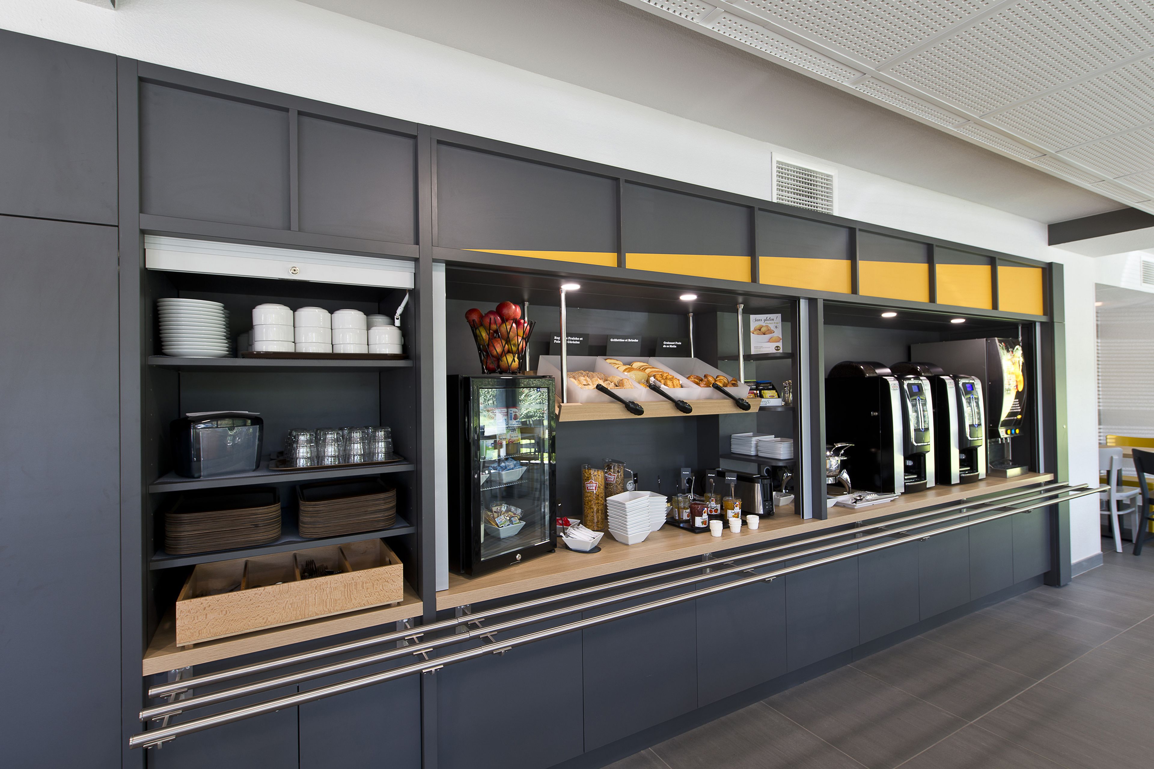 Uma estação de café da manhã com serviço de buffet, com diversos alimentos, acompanhamentos e uma máquina de café.