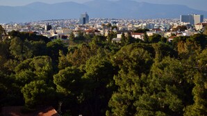Paisagem urbana com área densa, um edifício em destaque e uma cordilheira ao fundo.