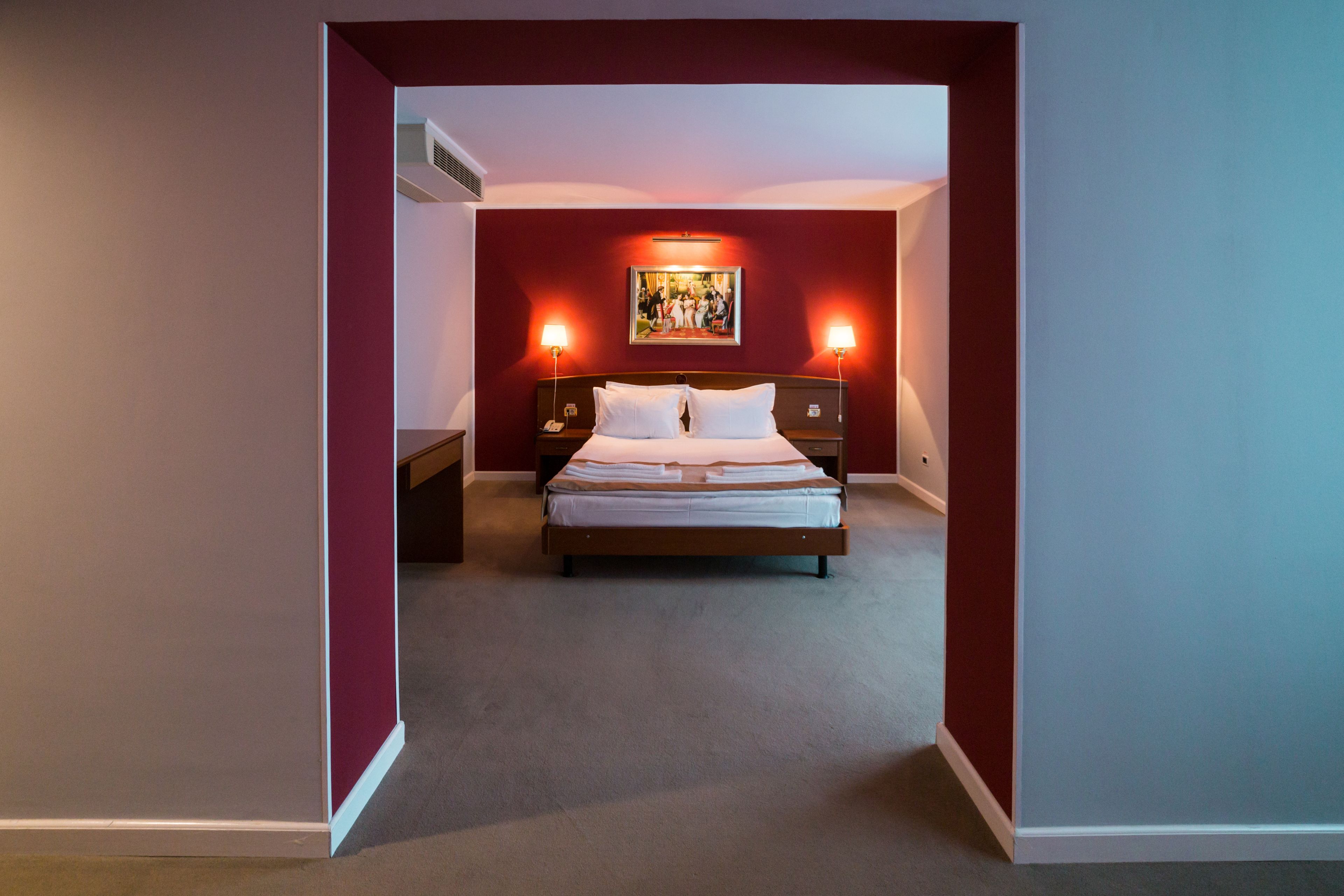 Quarto de hotel com uma cama, duas mesinhas de cabeceira e um quadro na parede.