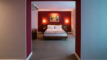 Quarto de hotel com uma cama, duas mesinhas de cabeceira e um quadro na parede.
