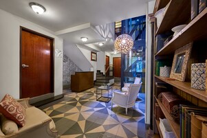 Um interior moderno com piso de padrão geométrico, escada, balcão de recepção e área de estar com luminária pendente única.