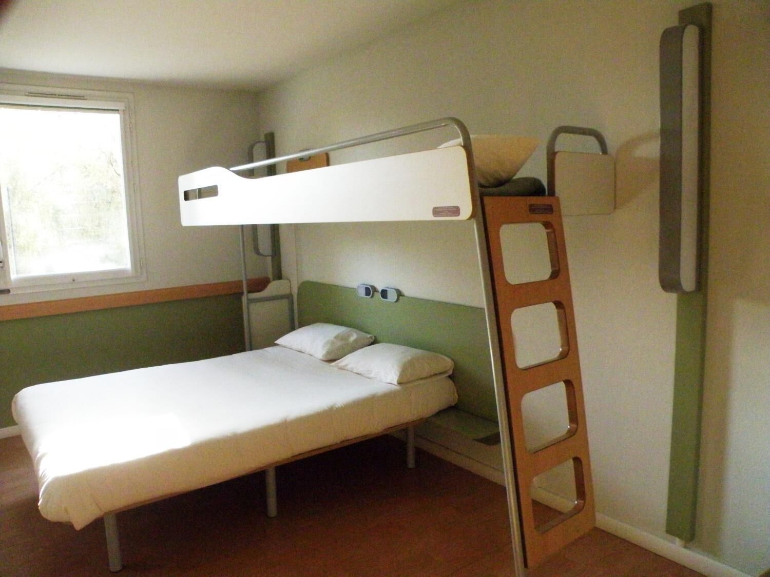 Uma cama beliche com escada, uma janela e uma prateleira fixada na parede.