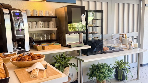Um balcão de pequeno-almoço com máquinas de café, uma vitrine e várias opções de comida.