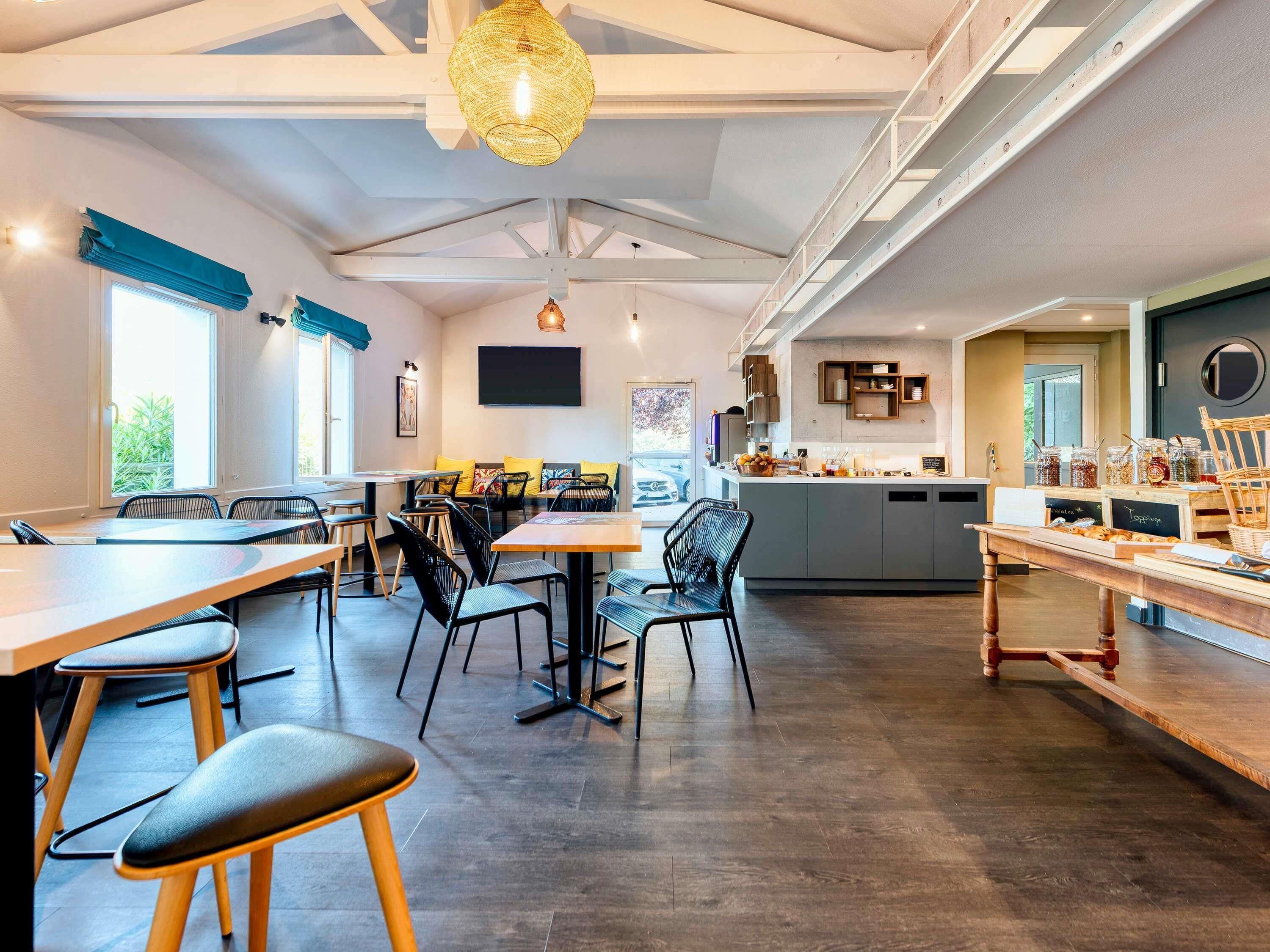 Um café moderno com balcão central, área de estar e bancada de cozinha com alimentos.