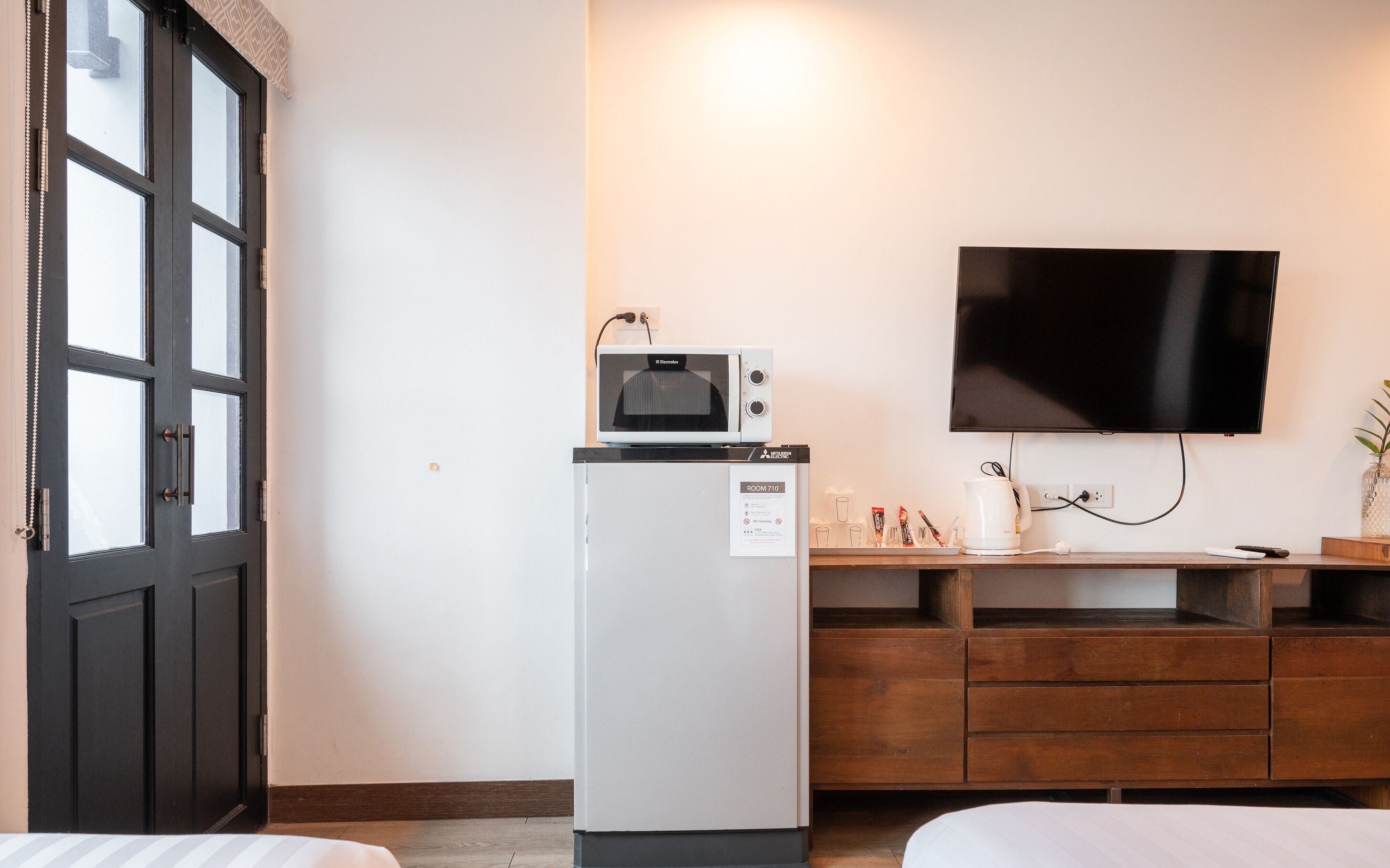 Quarto compacto com cozinha compacta, televisão de tela plana e um armário de madeira.