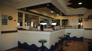 Uma área de bar com balcão, banquetes e uma máquina de café.