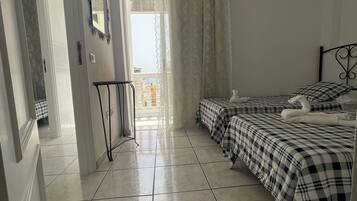 Quarto com duas camas, uma porta, um espelho e vista para o exterior.
