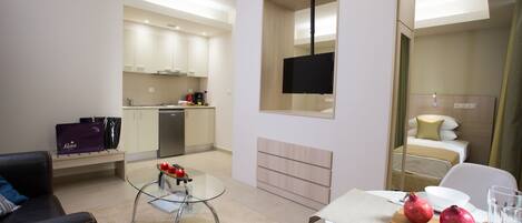 Quarto de hotel moderno com área de refeições, cozinha compacta e cama com vista.
