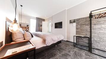 Quarto moderno com cama, mesa de cabeceira e TV fixada na parede.