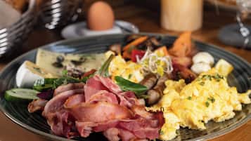 Prato de pequeno-almoço com ovos mexidos, bacon, cogumelos e legumes.