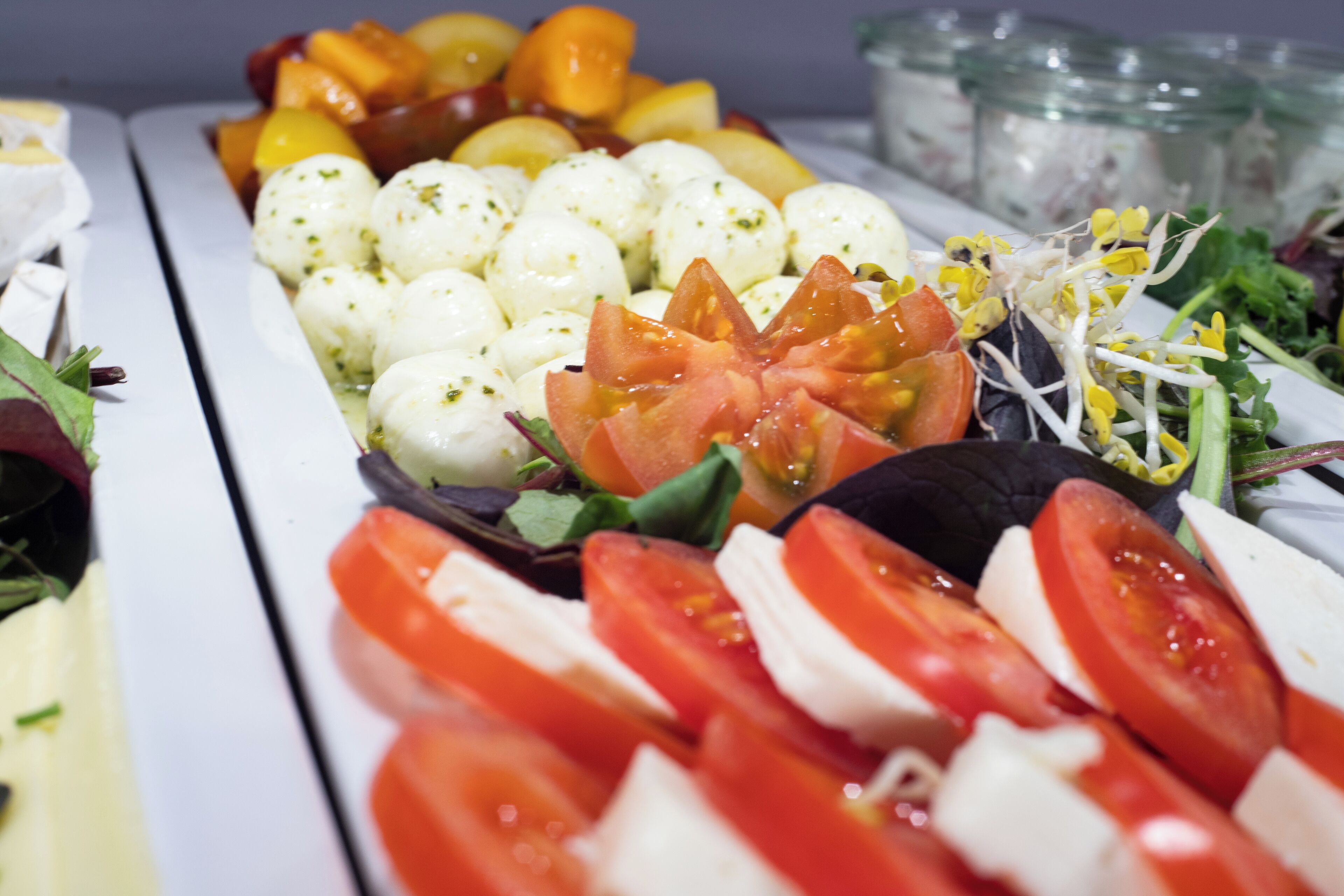 Diversos alimentos, incluindo tomates, bolinhas de mussarela e outros produtos frescos.
