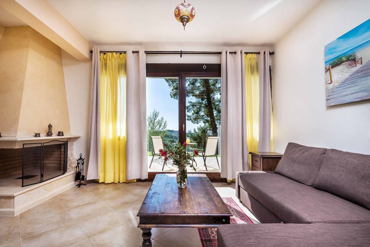 Uma sala de estar com sofá, mesa de centro de madeira e lareira.