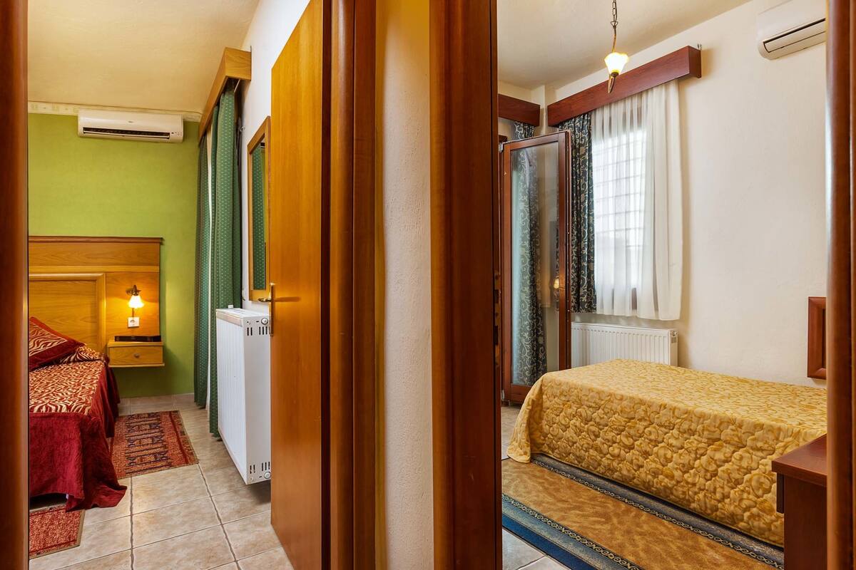 Quarto de hotel com cama, mesa de cabeceira, ar-condicionado e janela com cortinas.