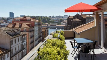 Um terraço com mesa e cadeiras, com vista para um horizonte urbano com edifícios históricos e um rio.