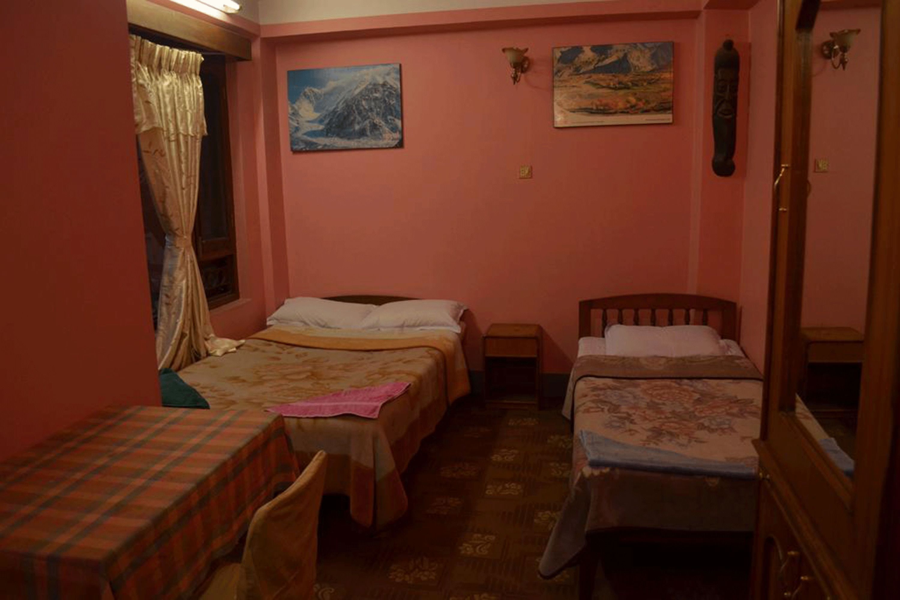Um quarto pequeno e acolhedor com duas camas, uma mesa e uma cadeira.