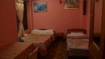 Um quarto pequeno e acolhedor com duas camas, uma mesa e uma cadeira.