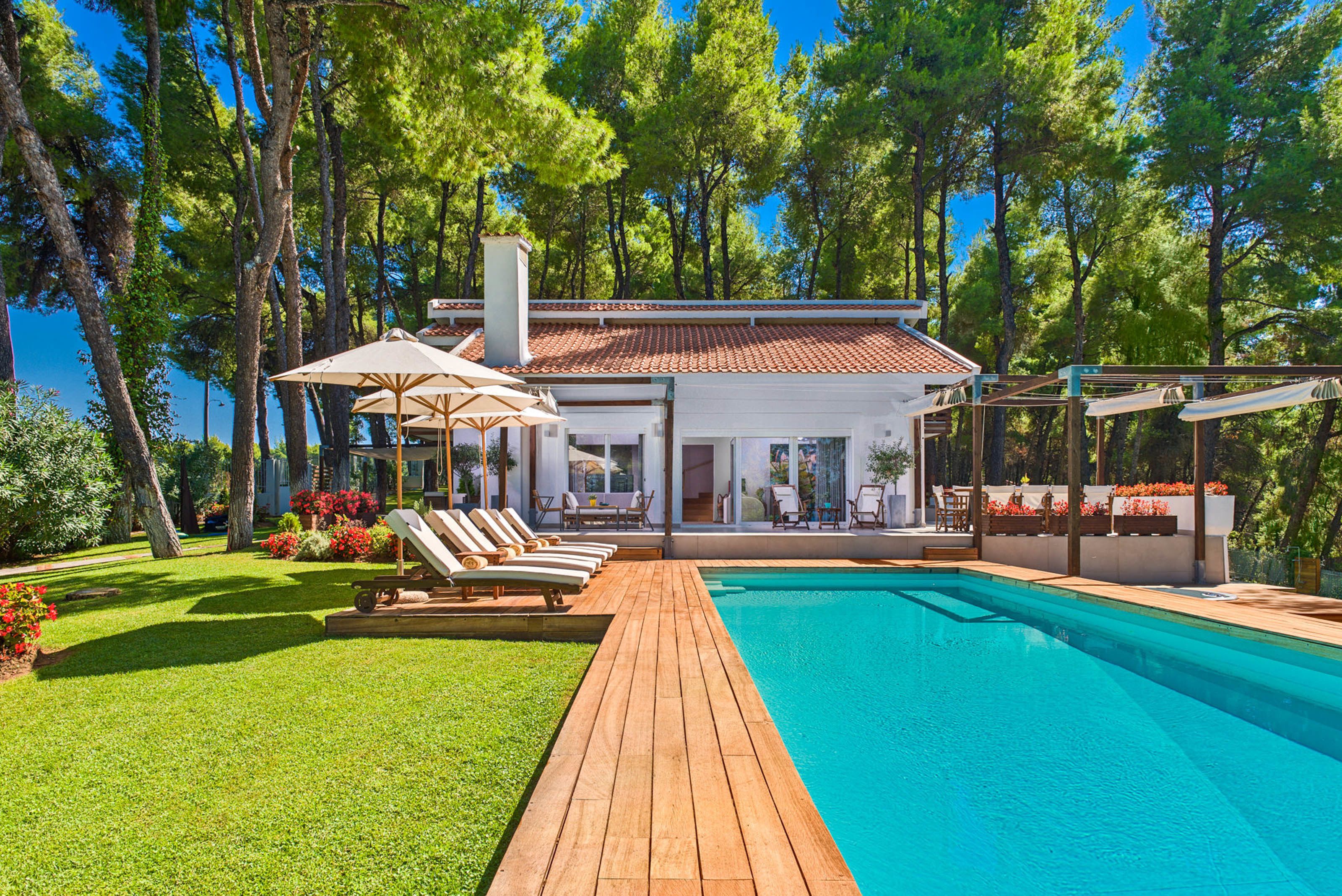 Uma casa moderna com piscina, cercada por vegetação exuberante e árvores.
