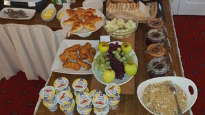 Um buffet de café da manhã com diversos alimentos, incluindo pães, frutas e potes de iogurte.