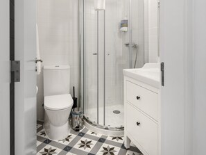 Uma casa de banho com sanita, cabine de duche e lavatório com espelho.