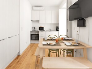 Uma cozinha compacta com armários brancos, micro-ondas, cafeteira e forno pequeno.