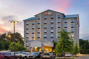 Um hotel Best Western Plus com design moderno, vários andares e um estacionamento com diversos carros.
