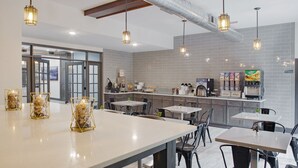 Uma cozinha moderna com bancada comprida, luminárias pendentes e um espaço para café.