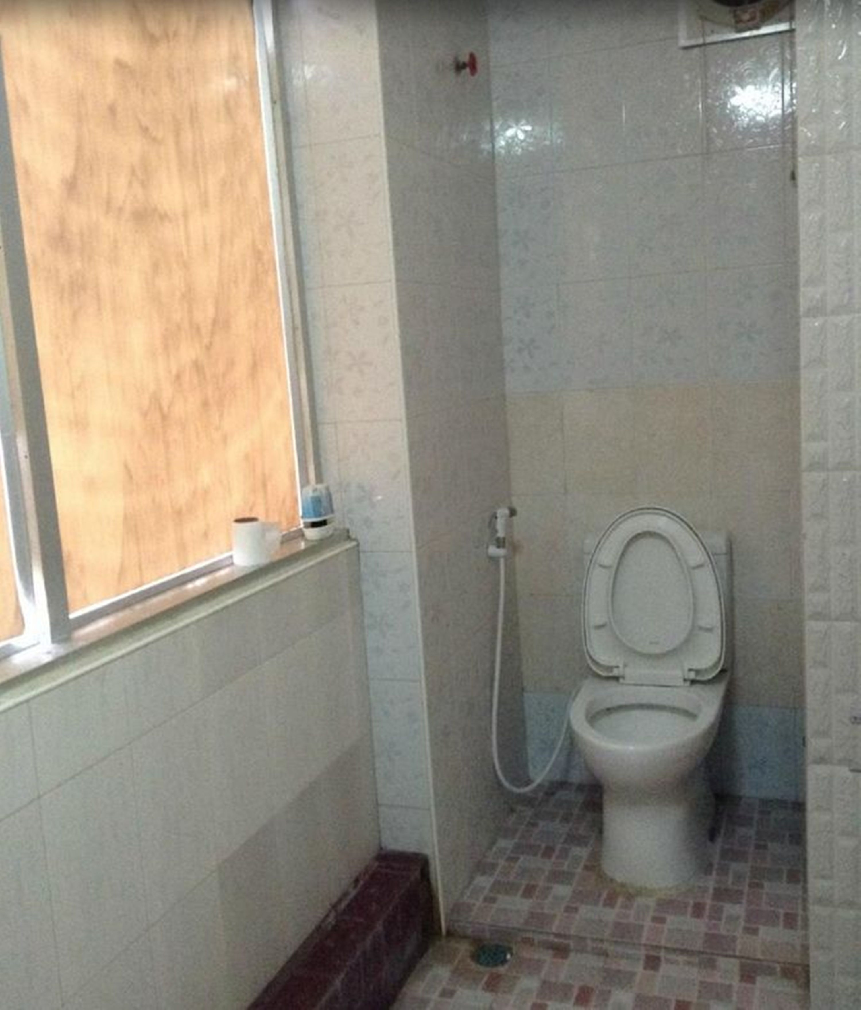 Um banheiro pequeno com vaso sanitário, chuveiro e janela.