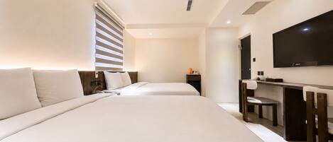 Quarto de hotel com duas camas, televisão, escrivaninha e uma cadeira.