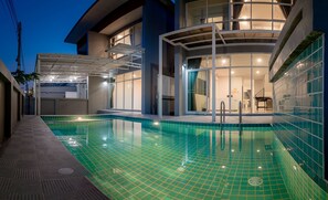 Um edifício moderno com piscina, janelas amplas e área externa coberta.