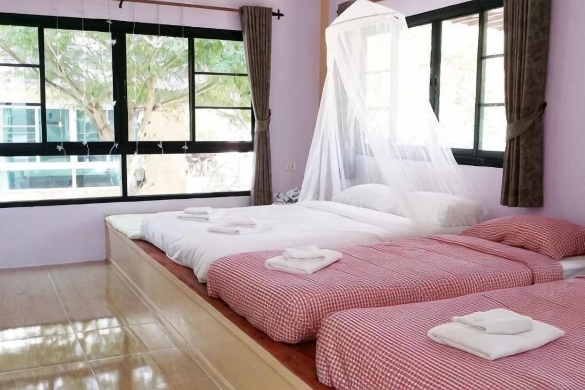 Um quarto com uma cama, uma janela e uma cortina.