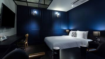 Quarto de hotel moderno com uma cama grande, luminárias de cabeceira, uma mesa e uma cadeira.