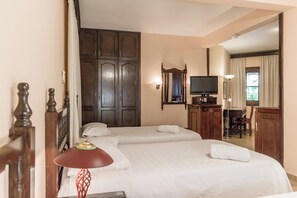 Quarto de hotel com duas camas, televisão, escrivaninha e espelho.
