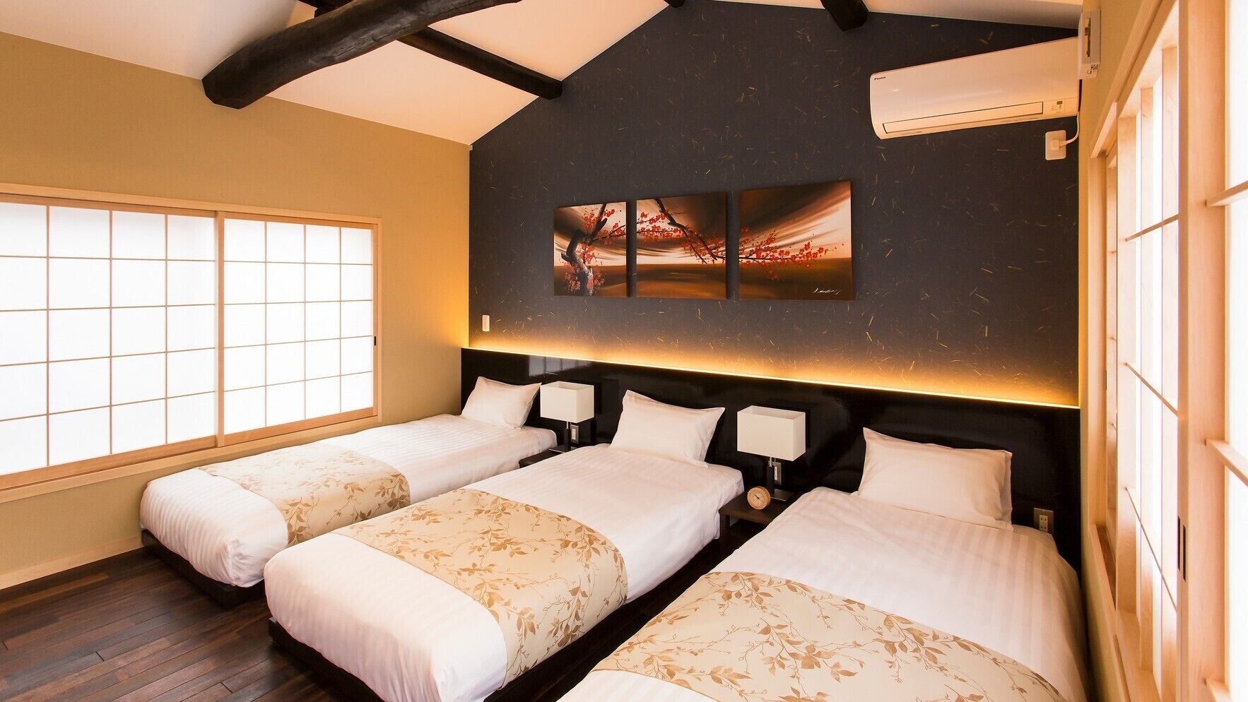 Quarto de hotel com duas camas, uma janela grande e uma obra de arte fixada na parede.