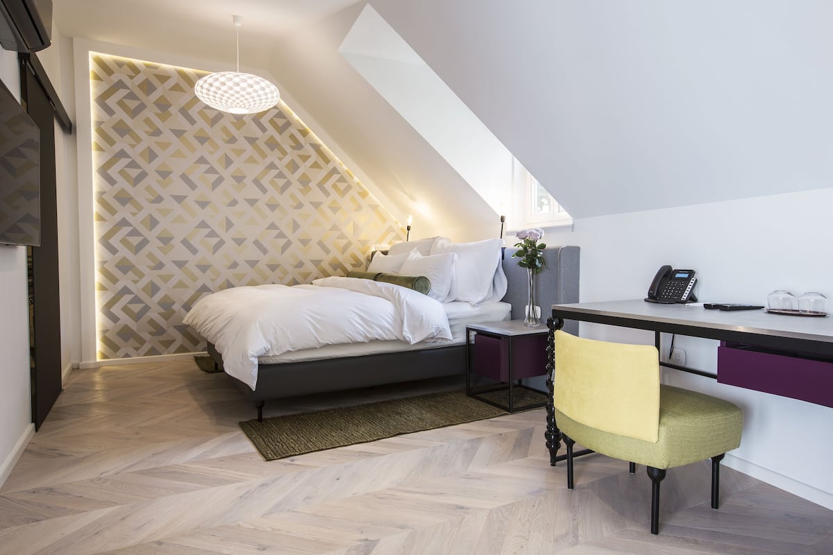 Quarto moderno com cama, escrivaninha, cadeira e parede com padrão geométrico.