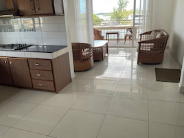 Uma cozinha moderna com ilha central, armários de madeira e área de jantar com móveis de vime, com vista para o exterior.