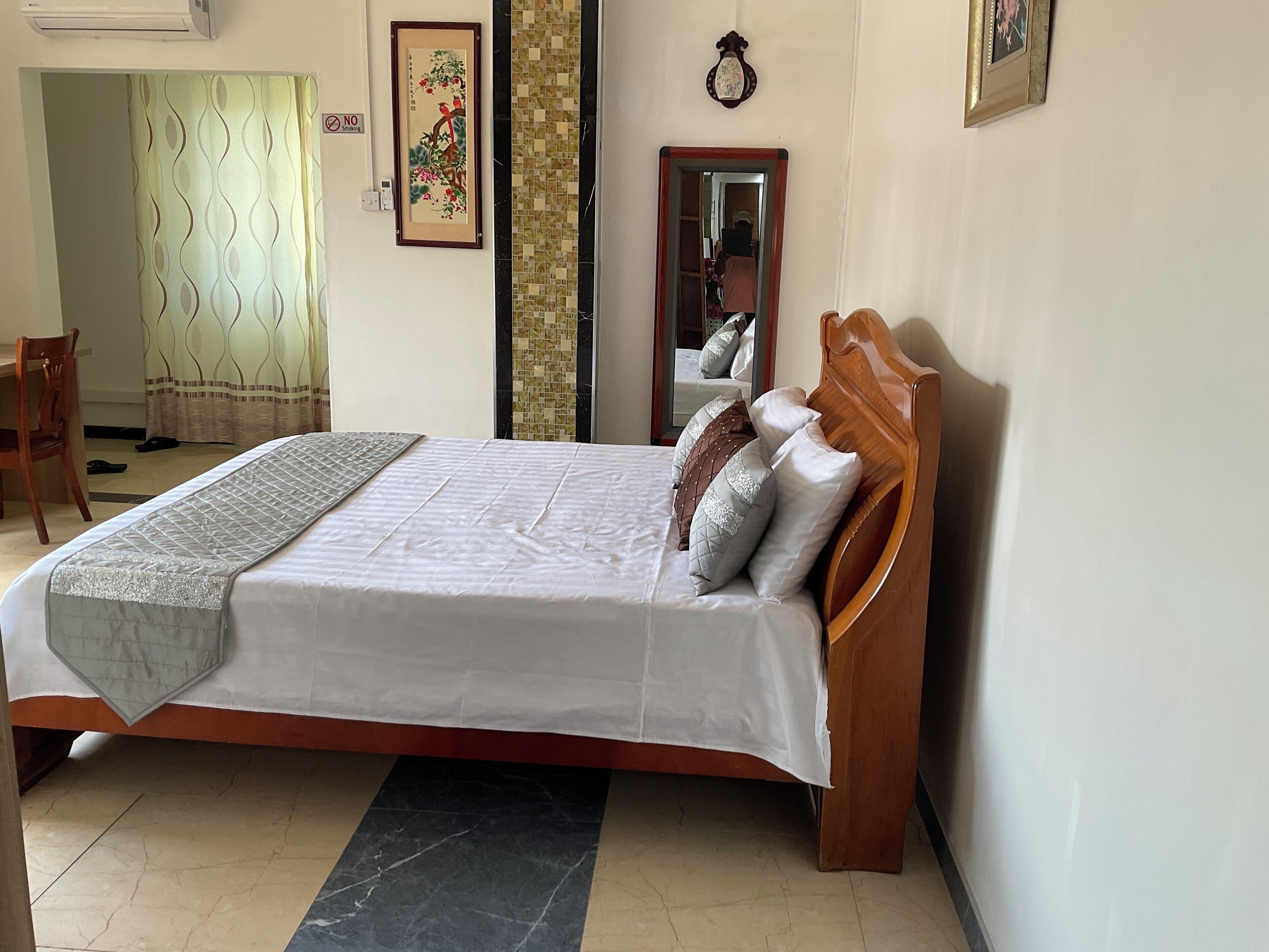 Uma cama bem arrumada com cabeceira de madeira, uma mesa de cabeceira e um espelho na parede.