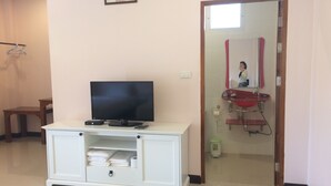 Quarto de hotel com um armário branco, uma televisão de tela plana, um espelho e uma pia vermelha.
