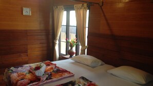 Quarto de cabana de madeira com duas camas, um relógio na parede e uma janela com cortinas.