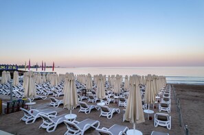 Uma praia privada, espreguiçadeiras, guarda-sóis de praia 
