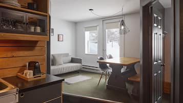Um quarto aconchegante com um armário de madeira, um sofá, uma mesa de jantar e uma janela.