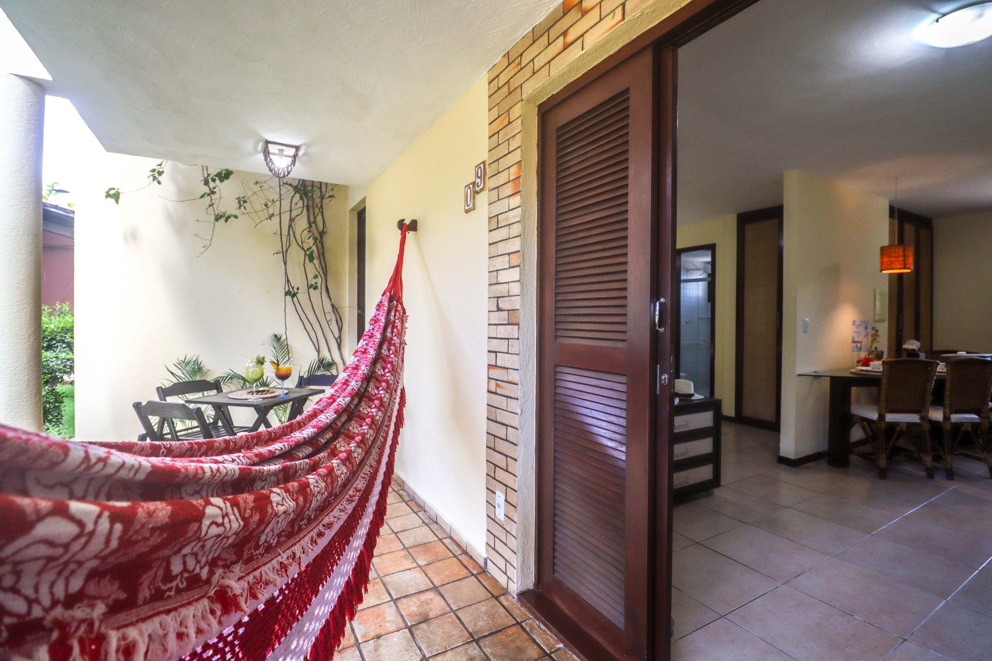 Um quarto com área de refeições, uma porta com número e uma rede.