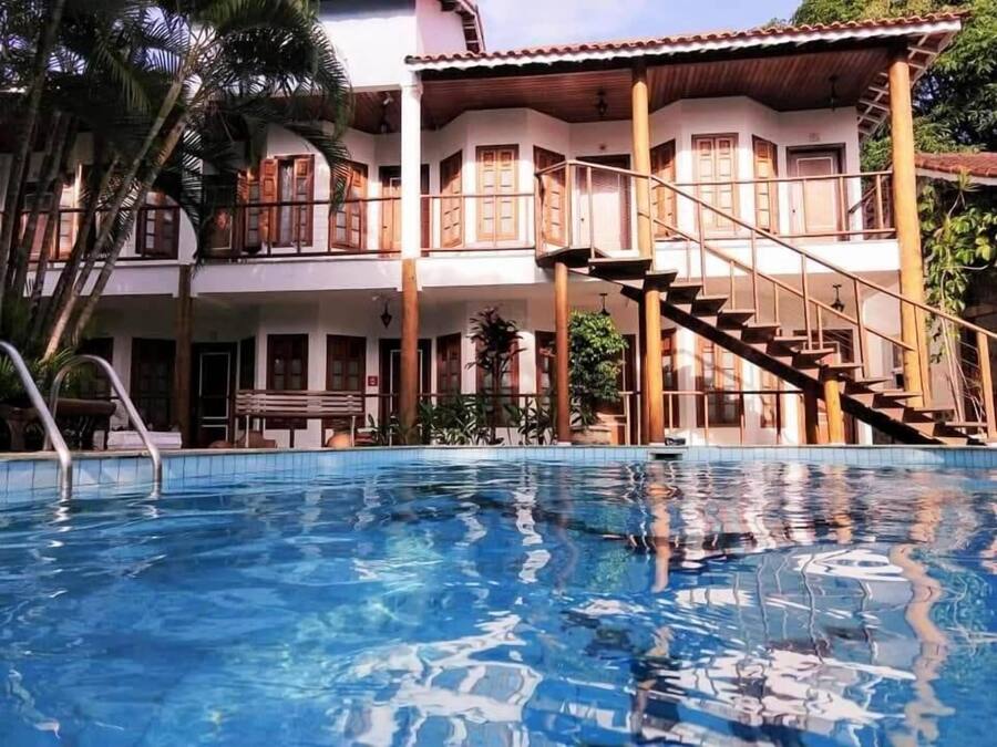 Um edifício de dois andares com piscina, varandas de madeira e escadaria que dá acesso ao nível superior.