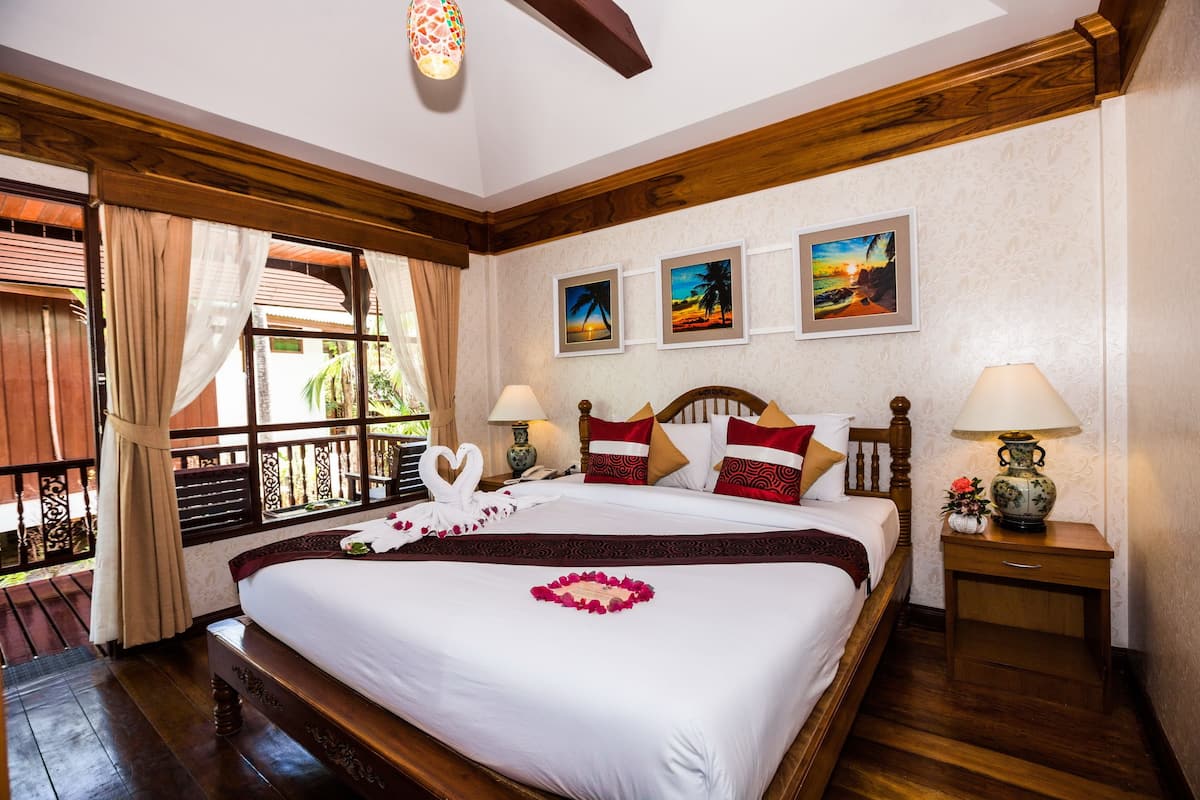 Quarto de hotel bem equipado, com uma cama grande, cabeceira de madeira e varanda com vista.