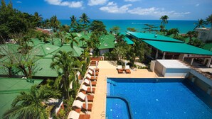 Um resort com piscina, espreguiçadeiras e vista para o oceano.