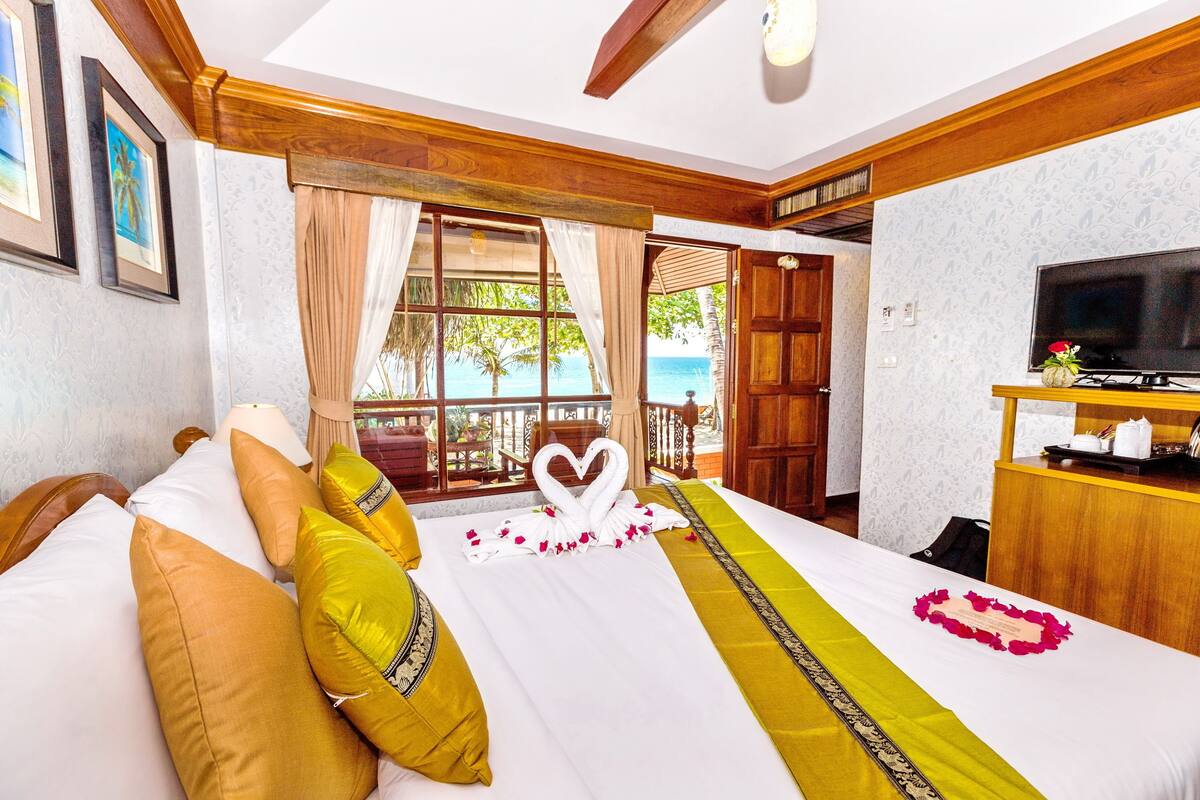 Quarto de hotel com cama, televisão e vista para o oceano.
