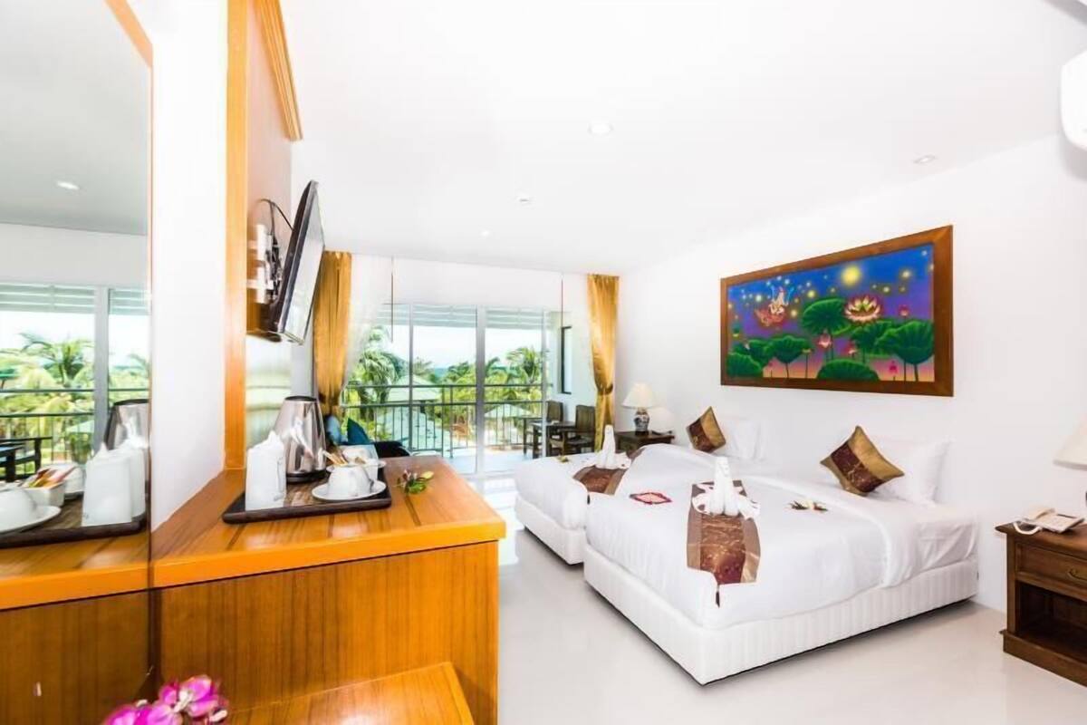 Quarto de hotel com cama, escrivaninha com cafeteira, televisão e pintura de uma cena noturna.
